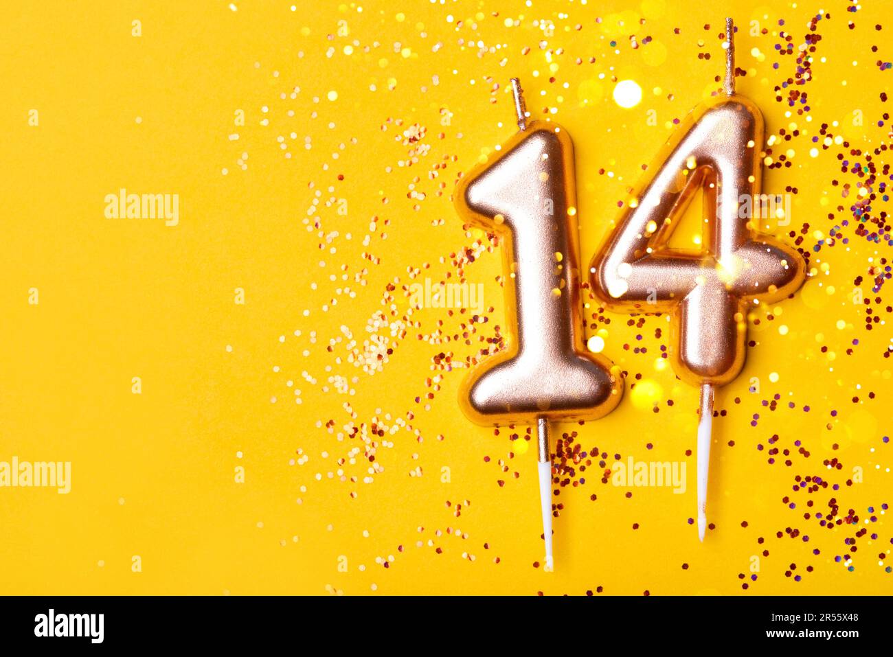 Gold candles in the form of number fourteen on yellow background with ...