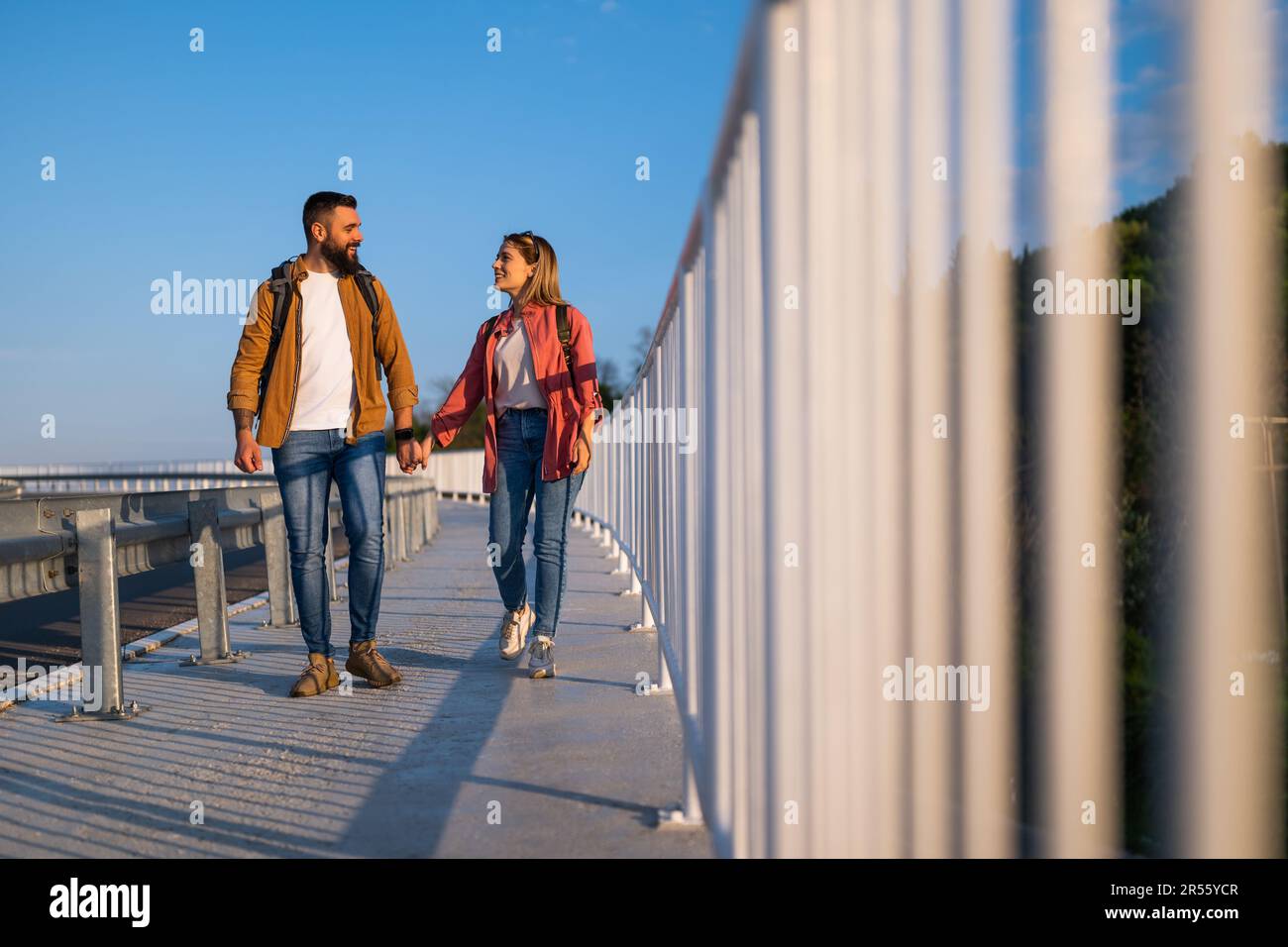 Happy couple holding hands and walking on pedestrian walkway. Tourists ...