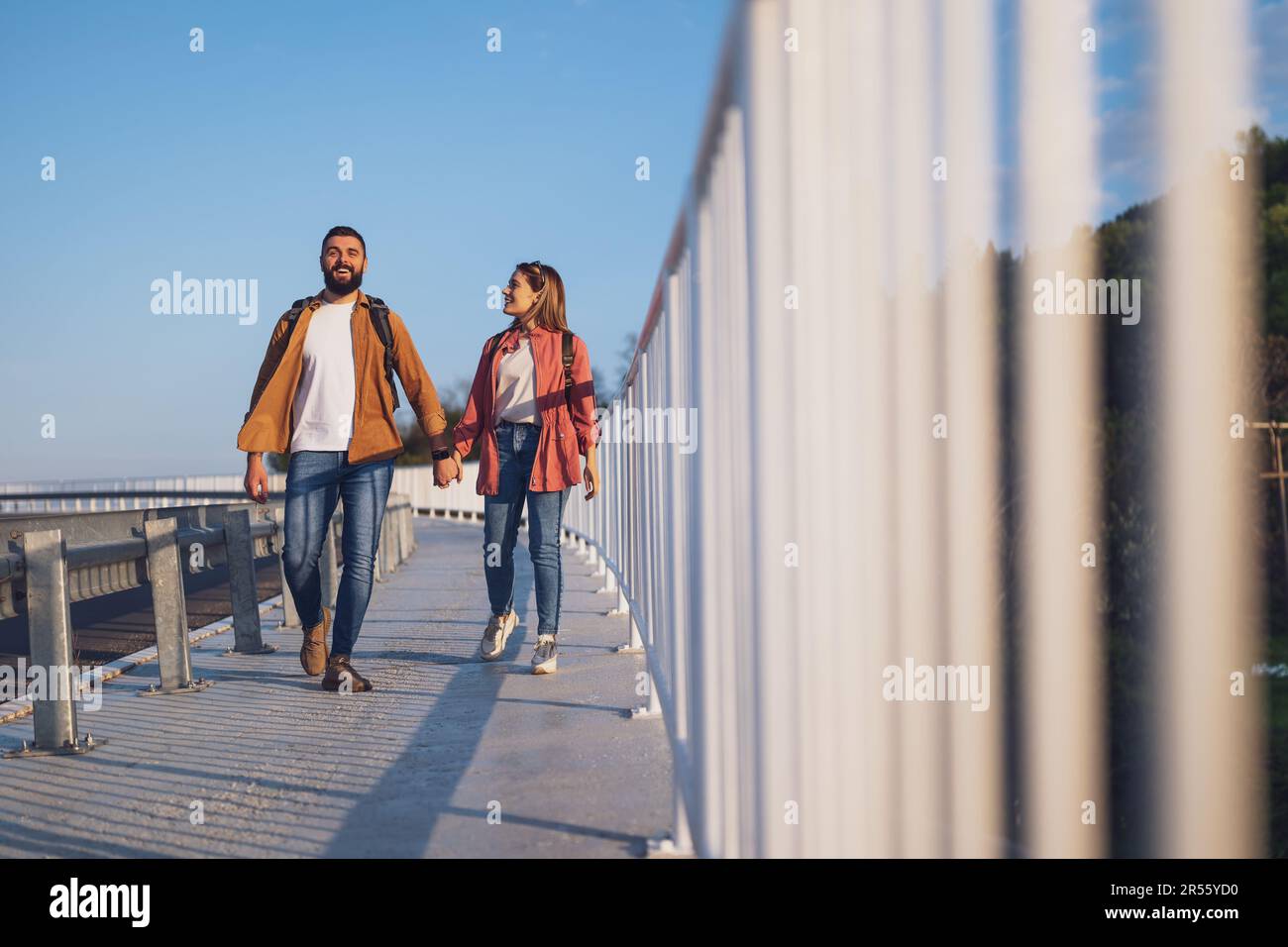 Happy couple holding hands and walking on pedestrian walkway. Tourists ...