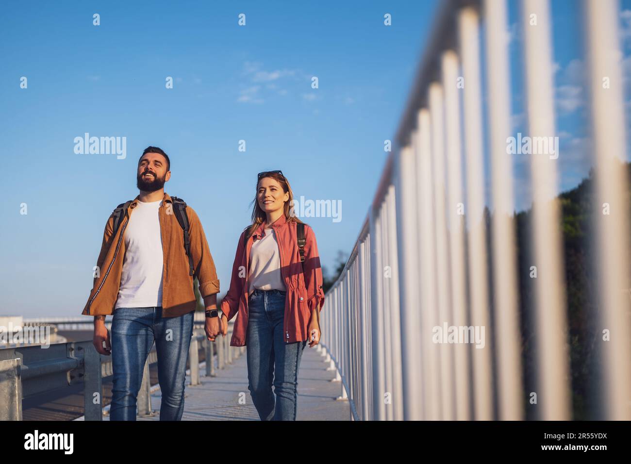 Happy couple holding hands and walking on pedestrian walkway. Tourists ...