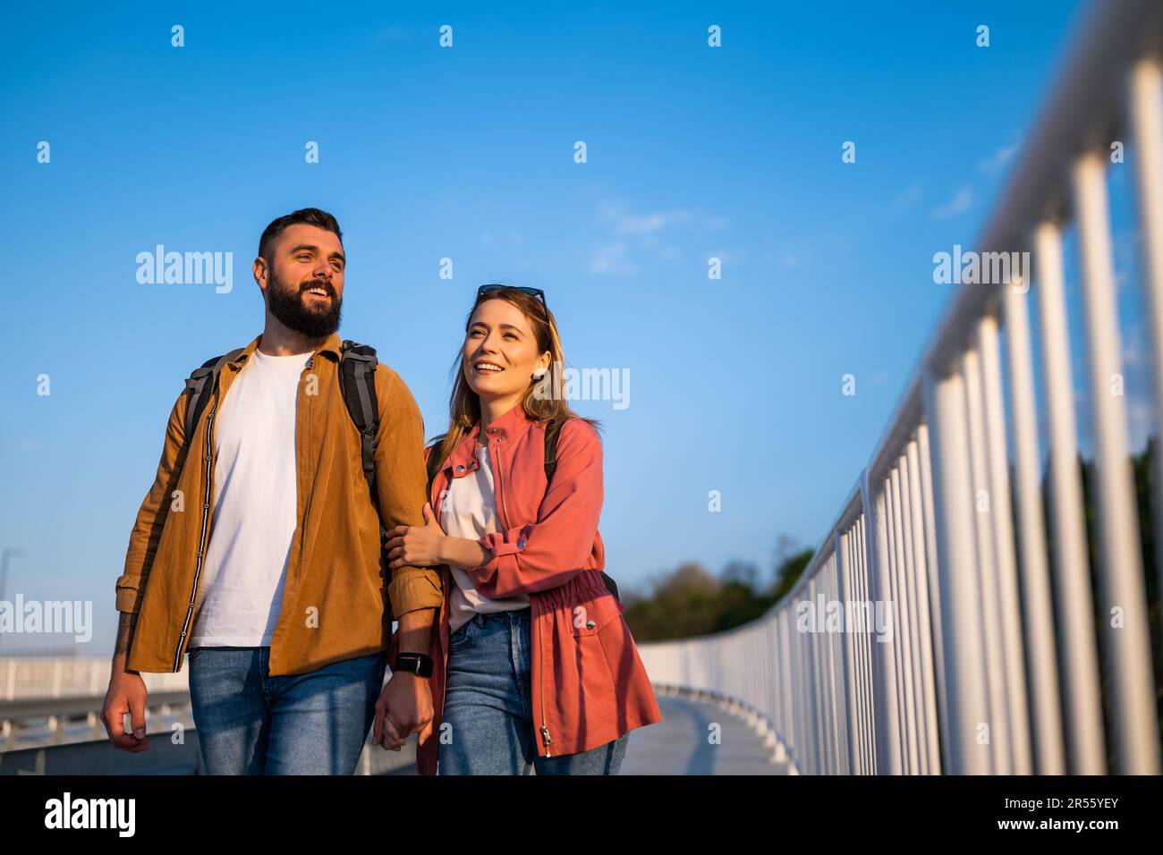 Happy couple holding hands and walking on pedestrian walkway. Tourists ...