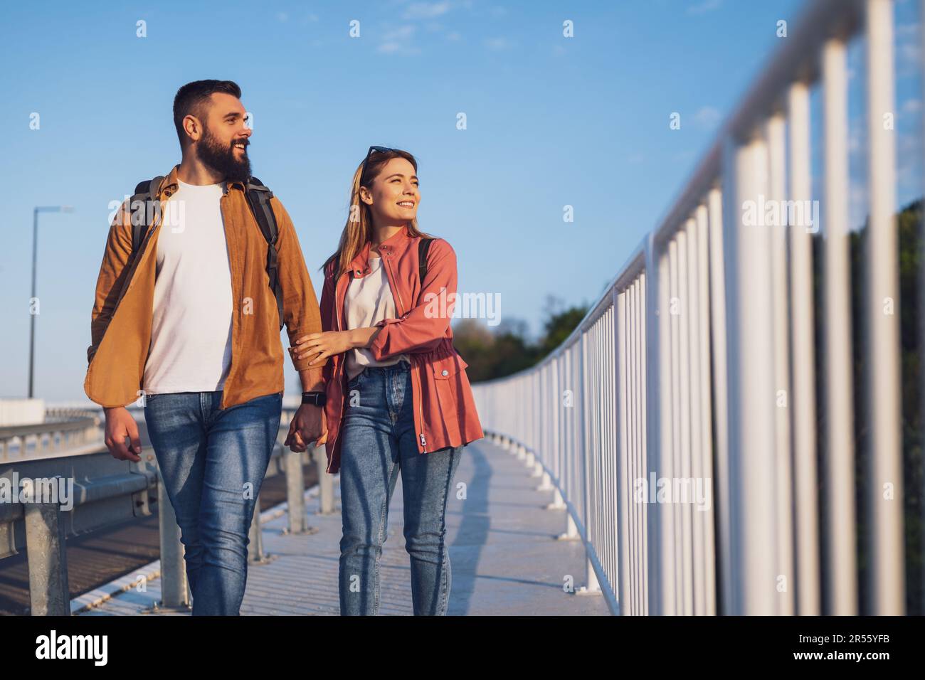 Happy couple holding hands and walking on pedestrian walkway. Tourists ...