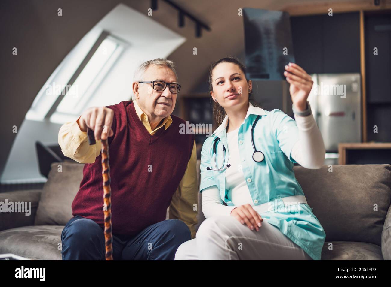 Home doctor is examining x-ray image with old man at his home ...
