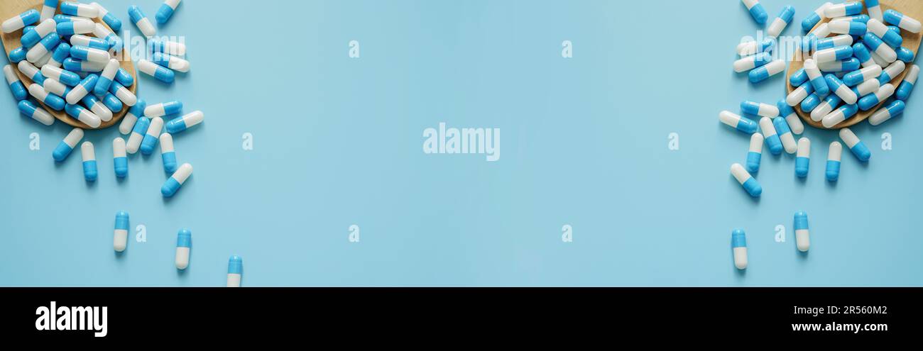 Blue and white antibiotic capsule pill and wooden spoon on blue ...