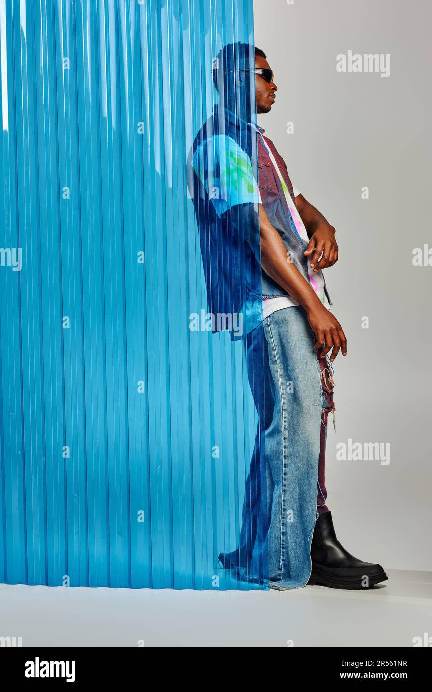 Side view of stylish afroamerican male model in ripped jeans, denim ...
