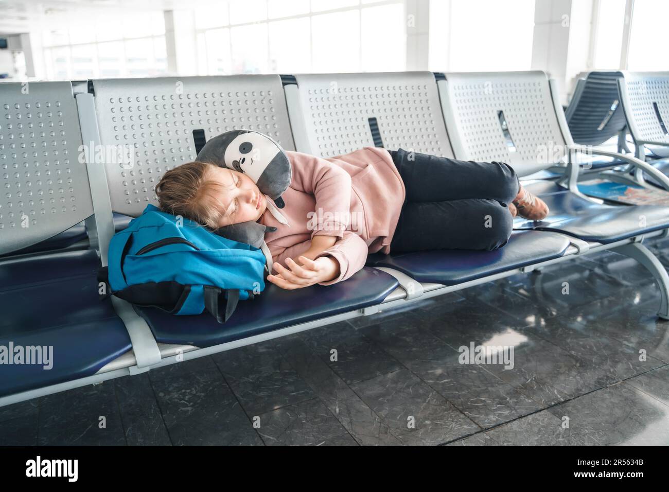 Kid, teen tired girl sleeping, waiting in airport passenger terminal departure hall with ...