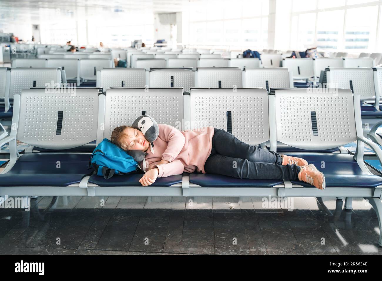 Kid, teen tired girl sleeping, waiting in airport passenger terminal departure hall with ...