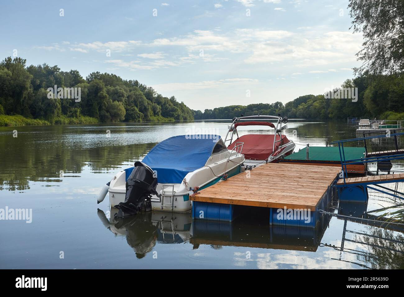 Lakeside pier with boats Stock Photo - Alamy