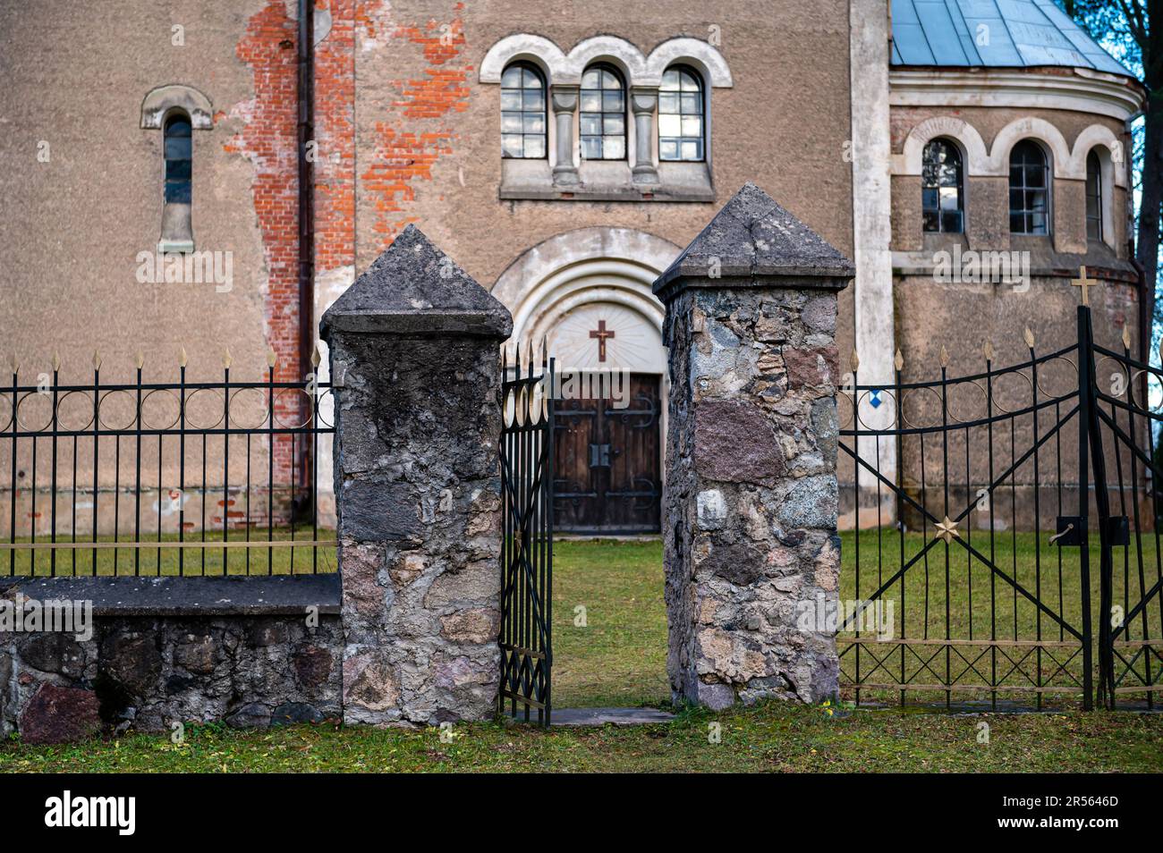 A fragment of a church fence with an open iron gate in the background ...