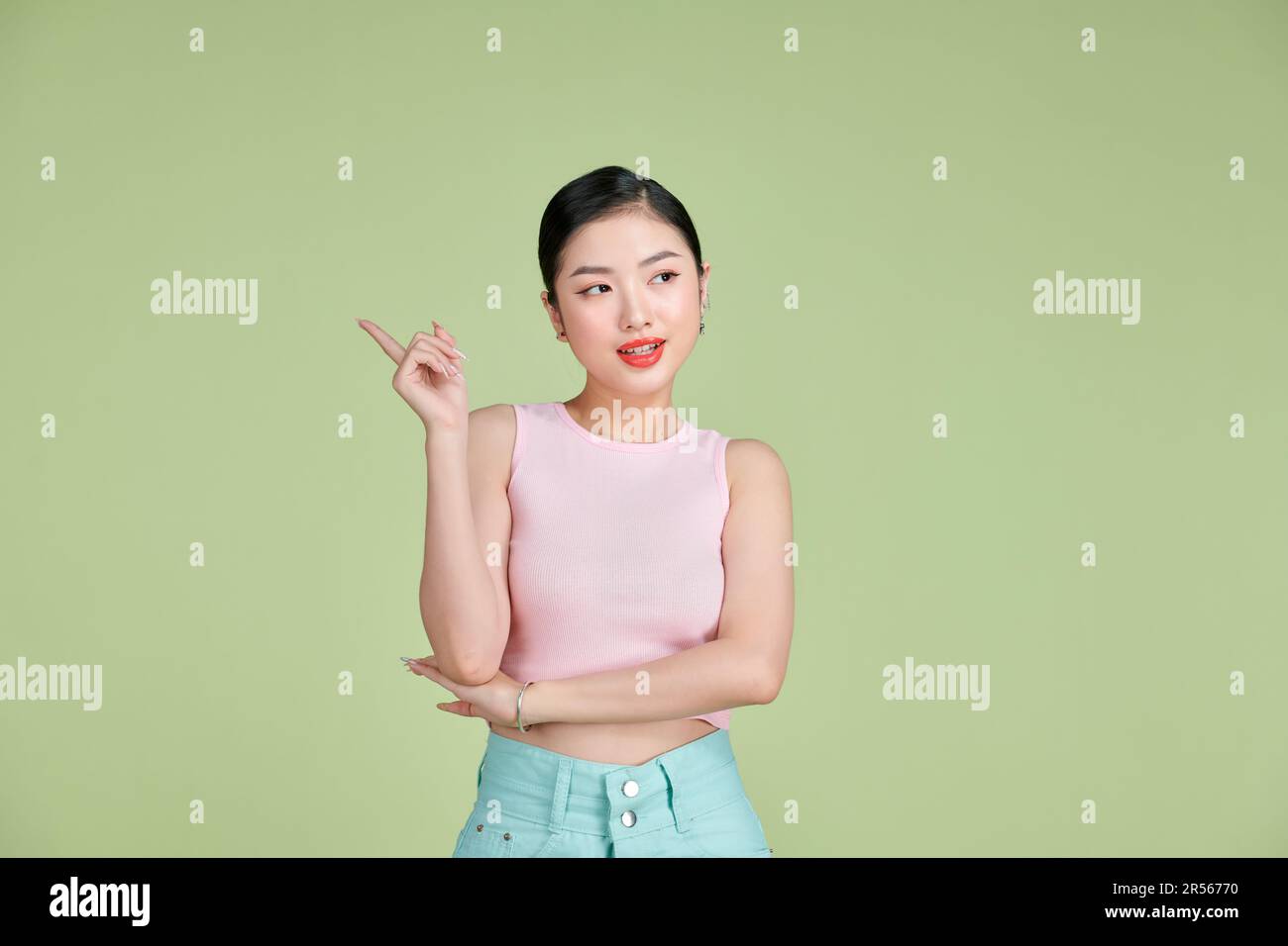 Portrait of Asian beautiful young woman pointing one hand with finger on side with smile face ...