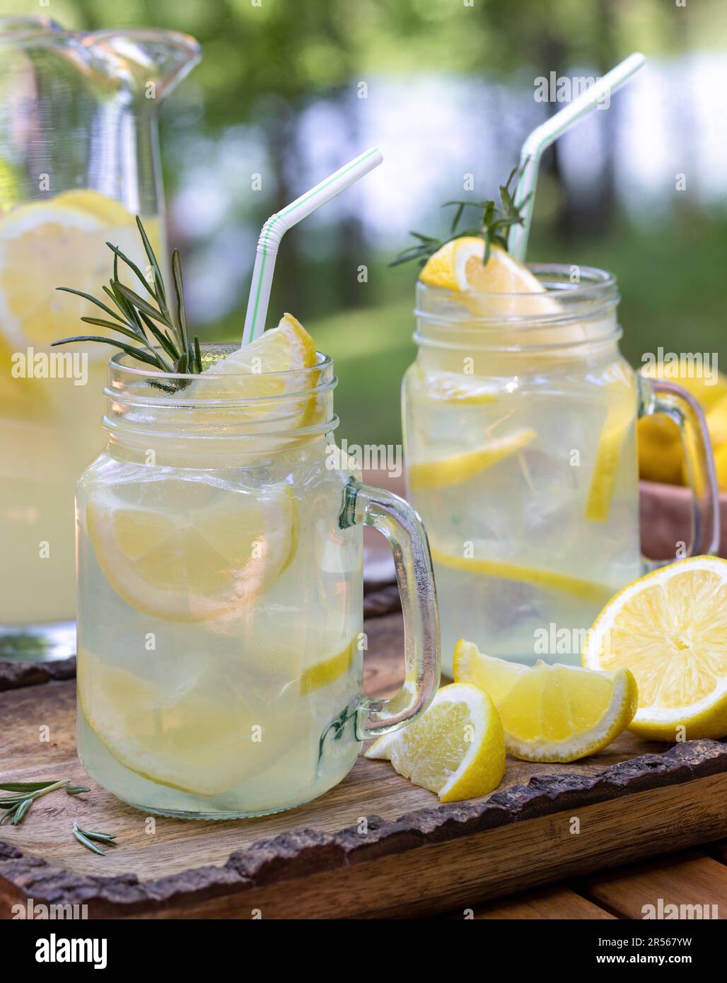Lemonade in two glass jars with lemon slices and rosemary on table ...