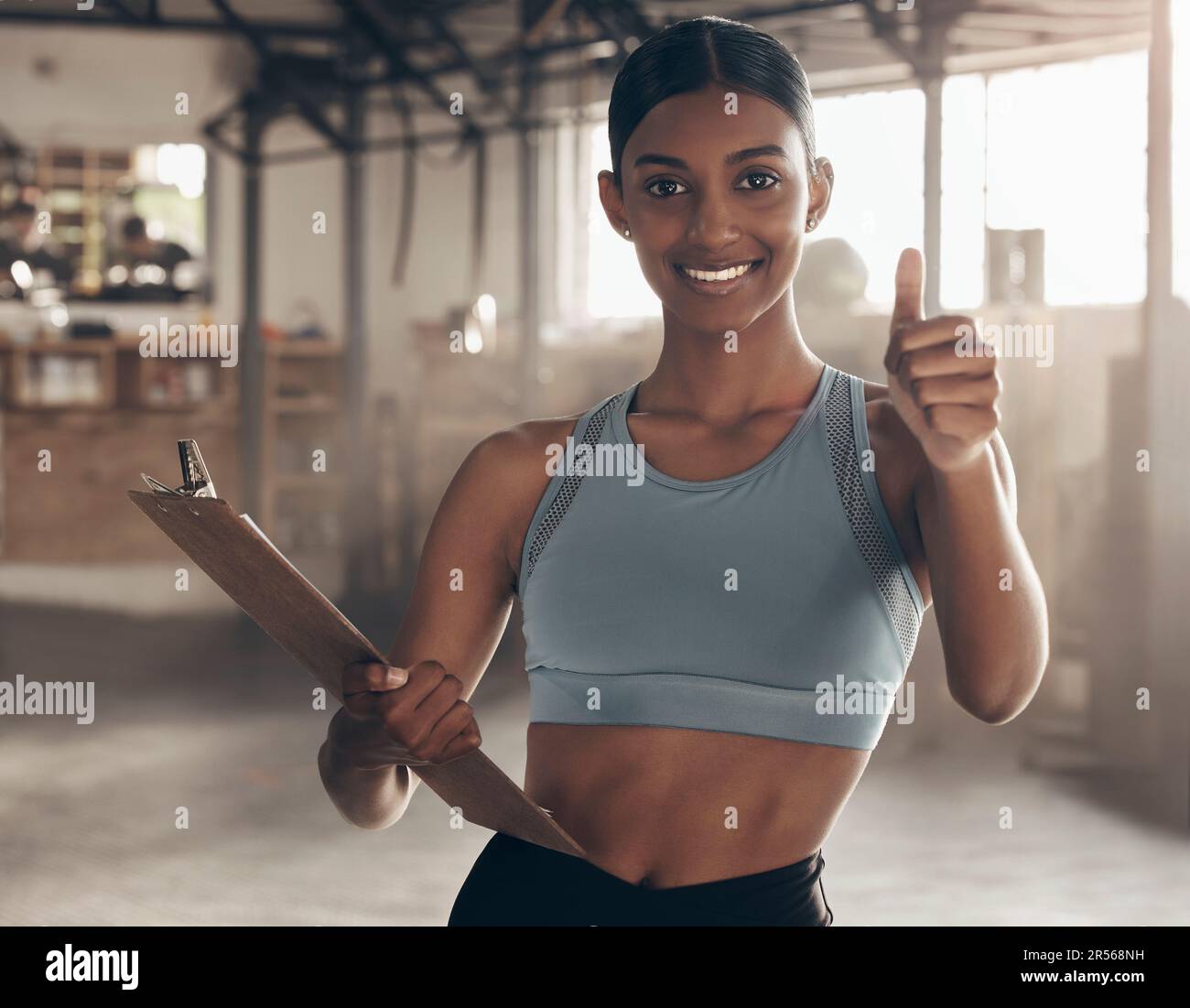 Thumbs up, clipboard and personal trainer with portrait of woman in gym ...