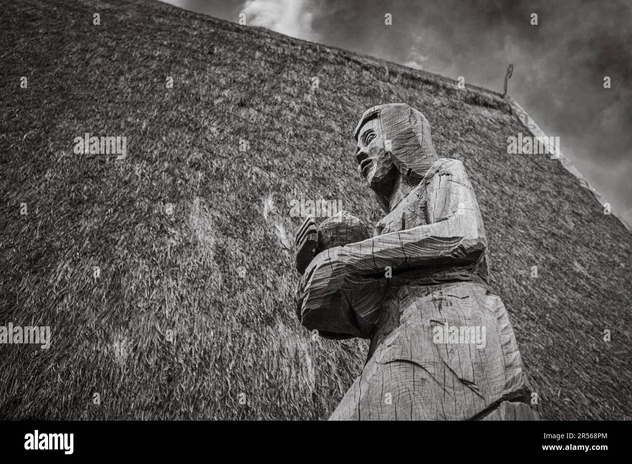 A carving of a kneeling woman holding a gourd stands guard at the ...