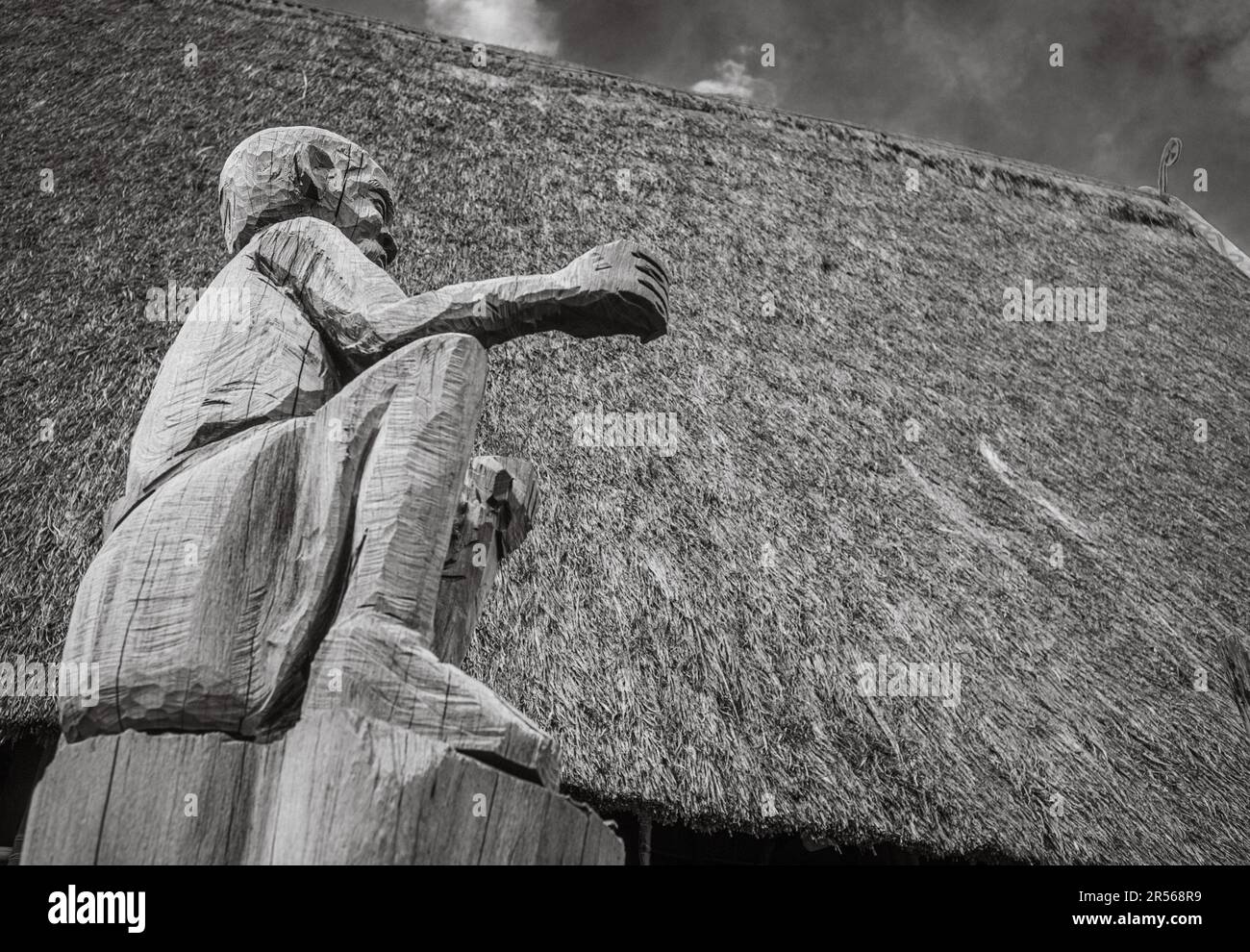 A carving of a man stands guard at the entrance of a traditional "nha ...