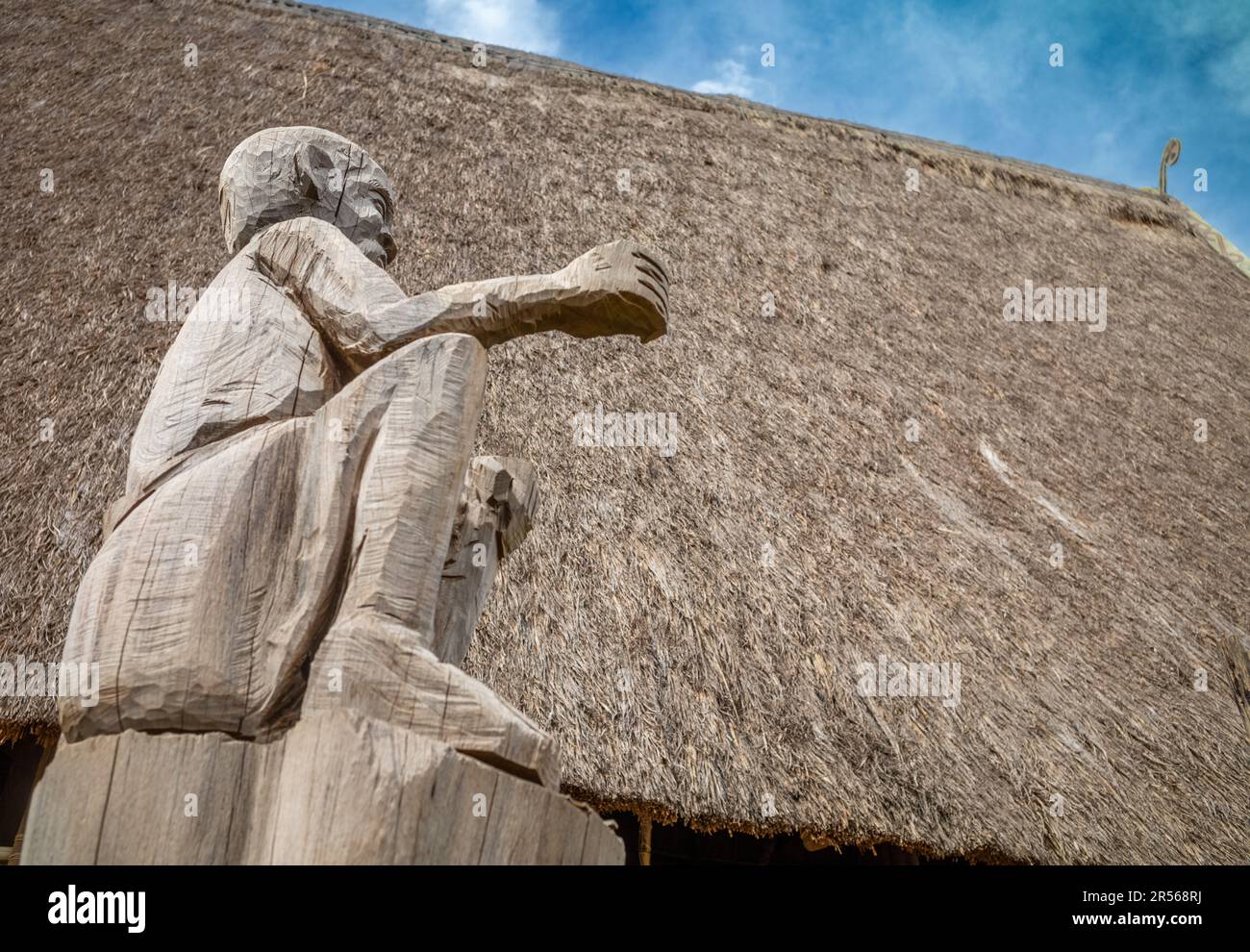 A carving of a man stands guard at the entrance of a traditional "nha ...
