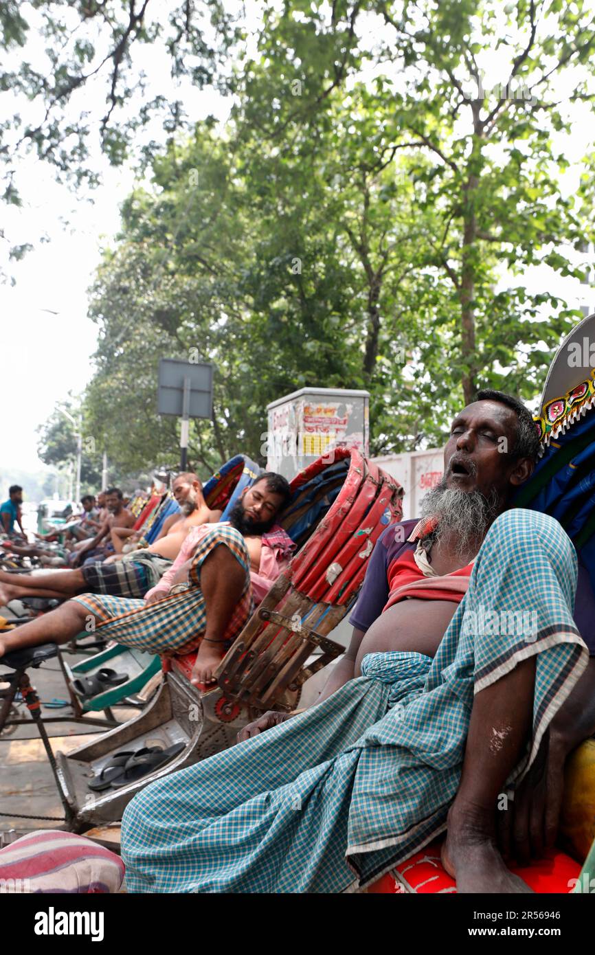 Dhaka, Bangladesh - June 01, 2023: In extreme heat tired rickshaw pullers are sleeping under the ...