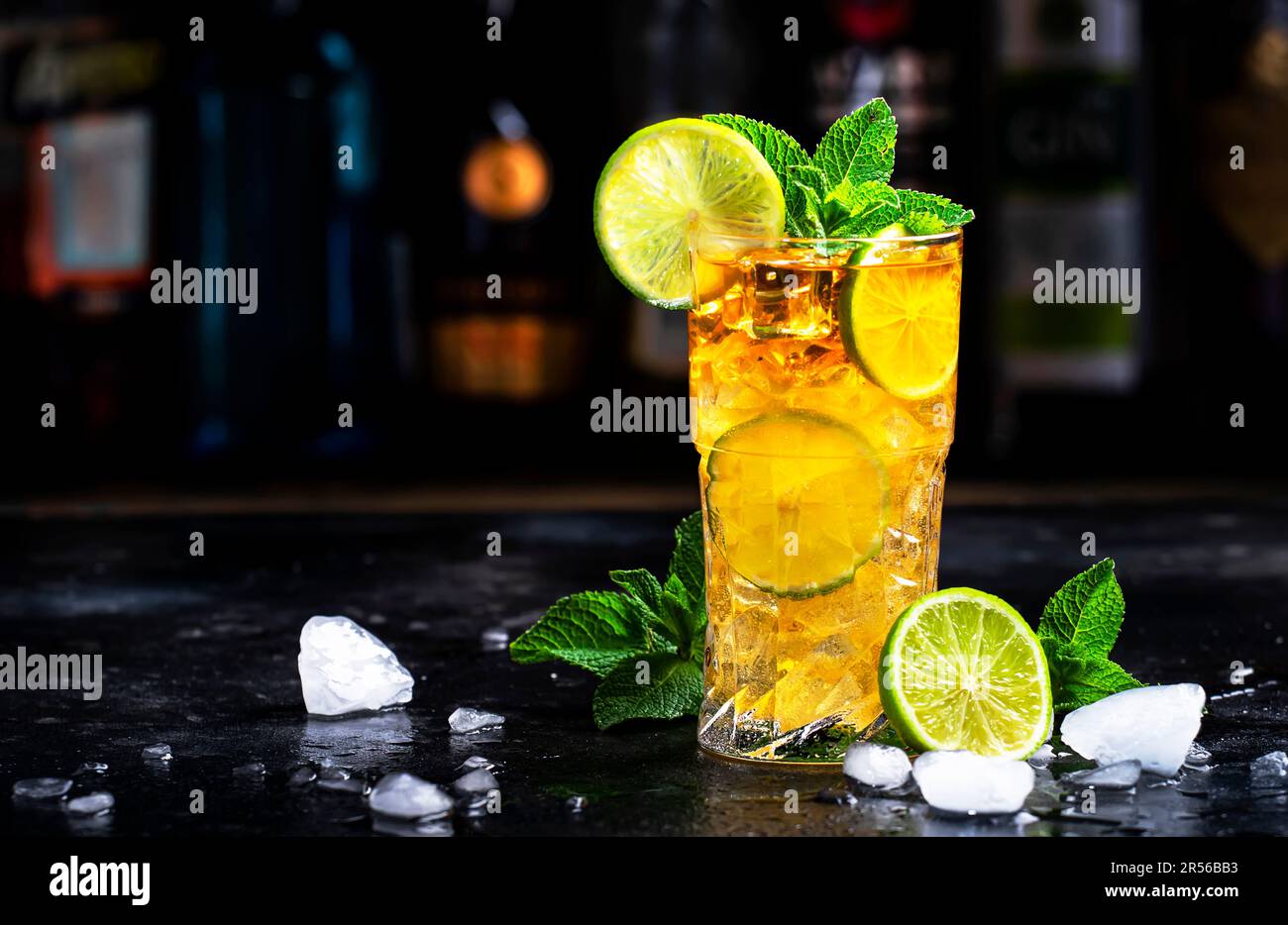 Dark and Stormy alcoholic cocktail drink with dark rum, ginger ale, lime and ice, black bar ...