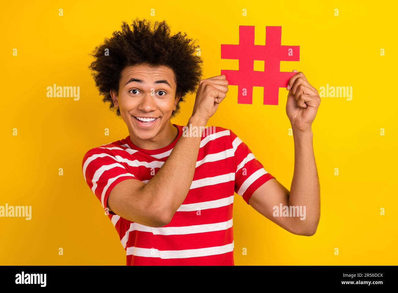 Photo of cheerful positive guy dressed red t-shirt smiling rising hash ...