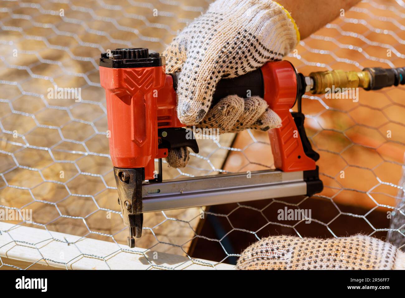 Work of worker involves nailing metal mesh to wooden frame by means ...