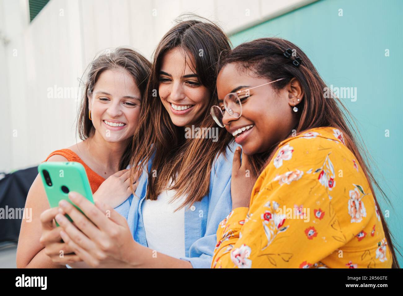 Group of young women smiling and having fun using a cellphone. Three ...