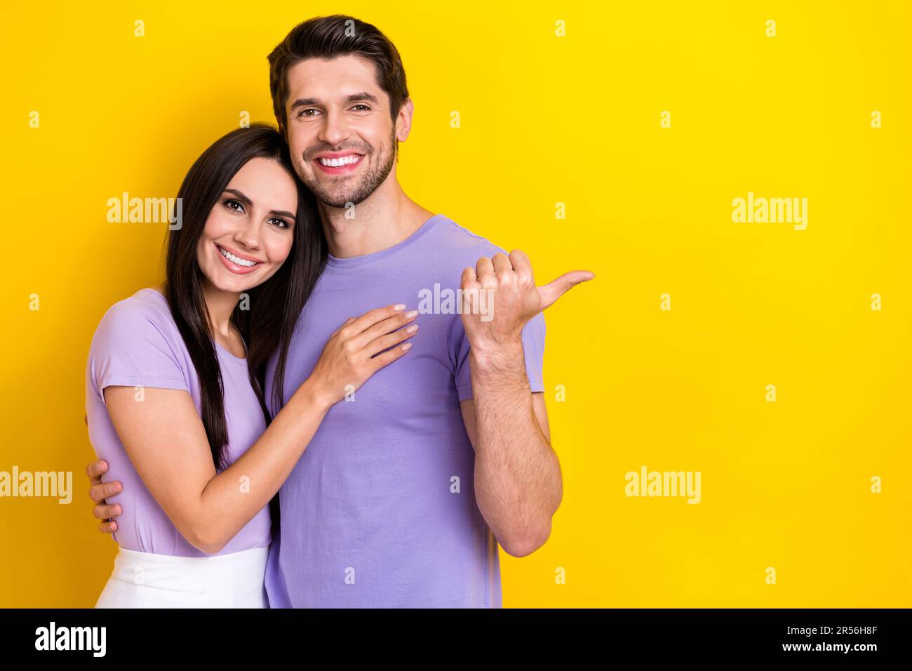 Portrait of two cheerful lovely people hug indicate finger empty space ...