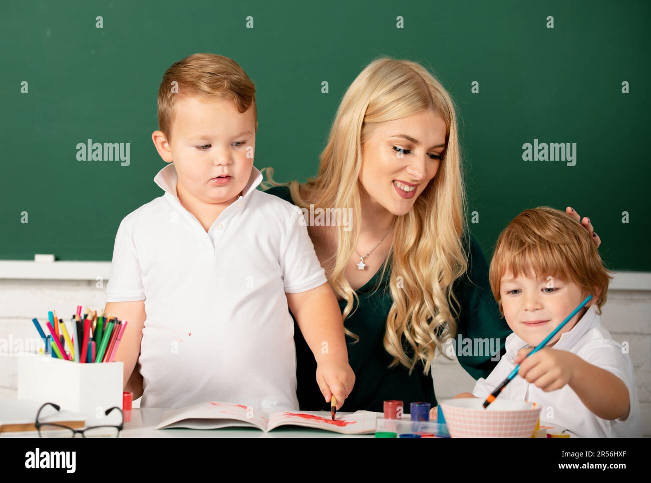 Little children with kindergarten teacher drawing at table indoors ...