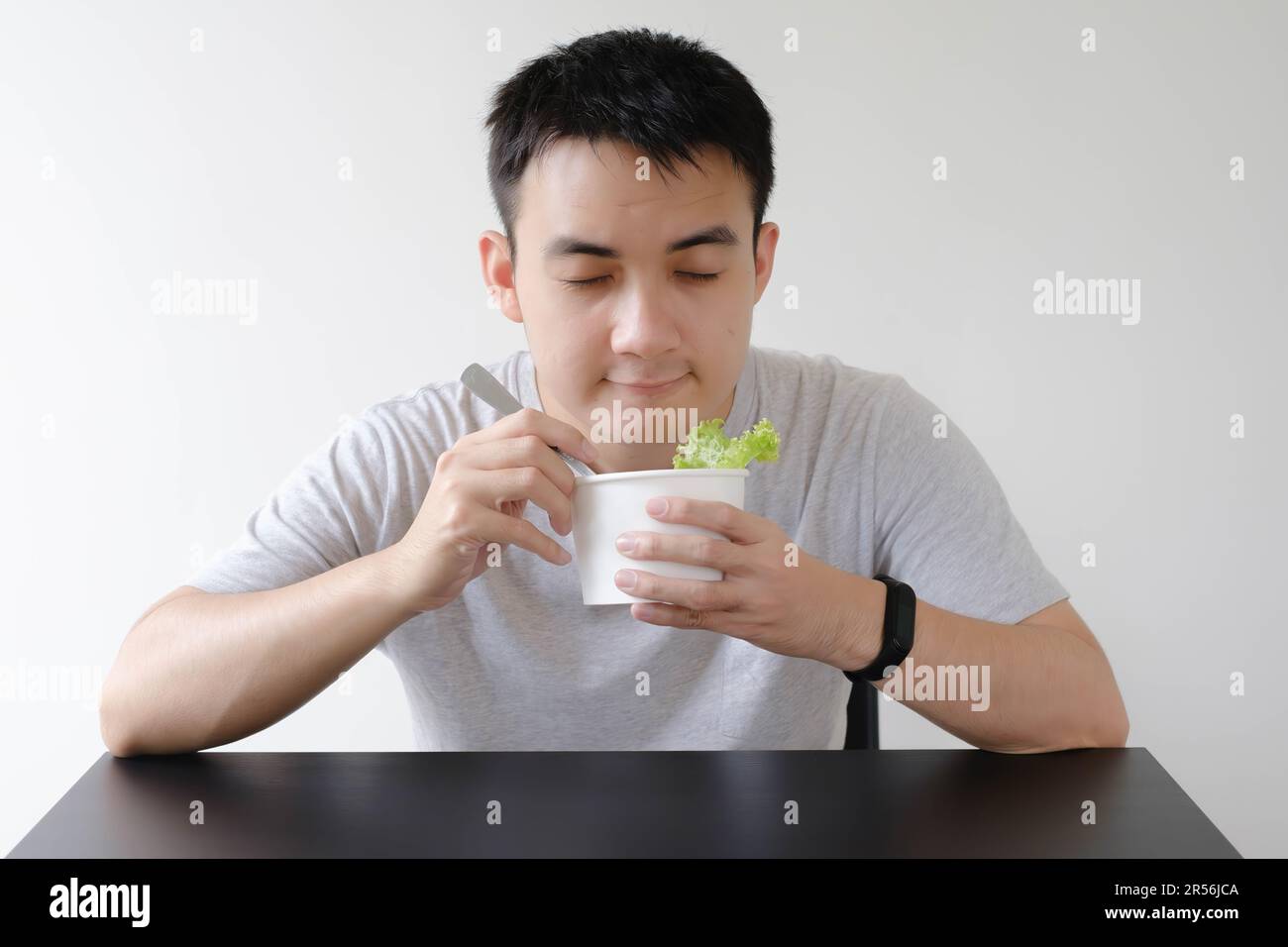 A young Asian man wearing a grey shirt and a smartwatch on his left ...