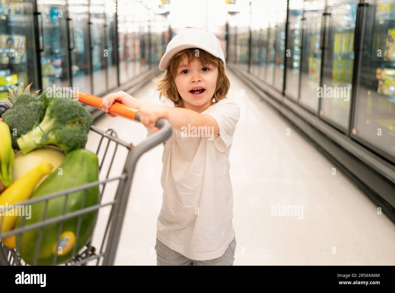 Joyful child boy in supermarket buys vegetables. Healthy food for ...