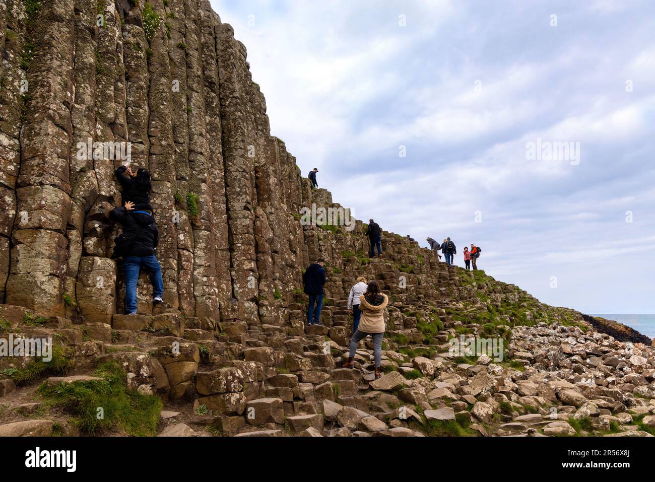 Tourists exploring the layered cliff face of the Giant's Causeway ...