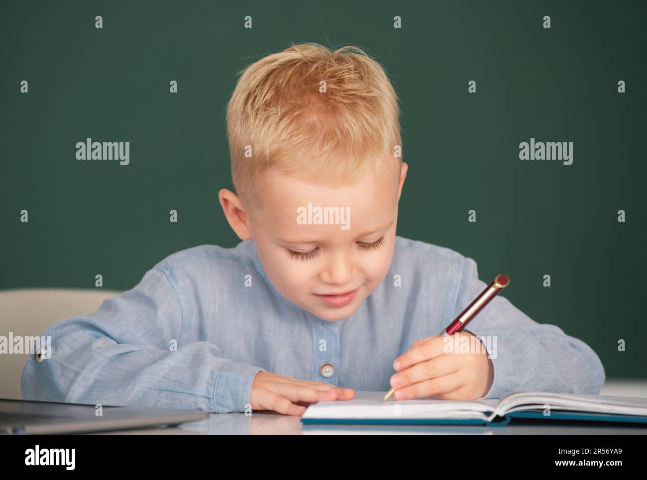 Child at school. Kid writing in notebook in class. Kid is learning in ...