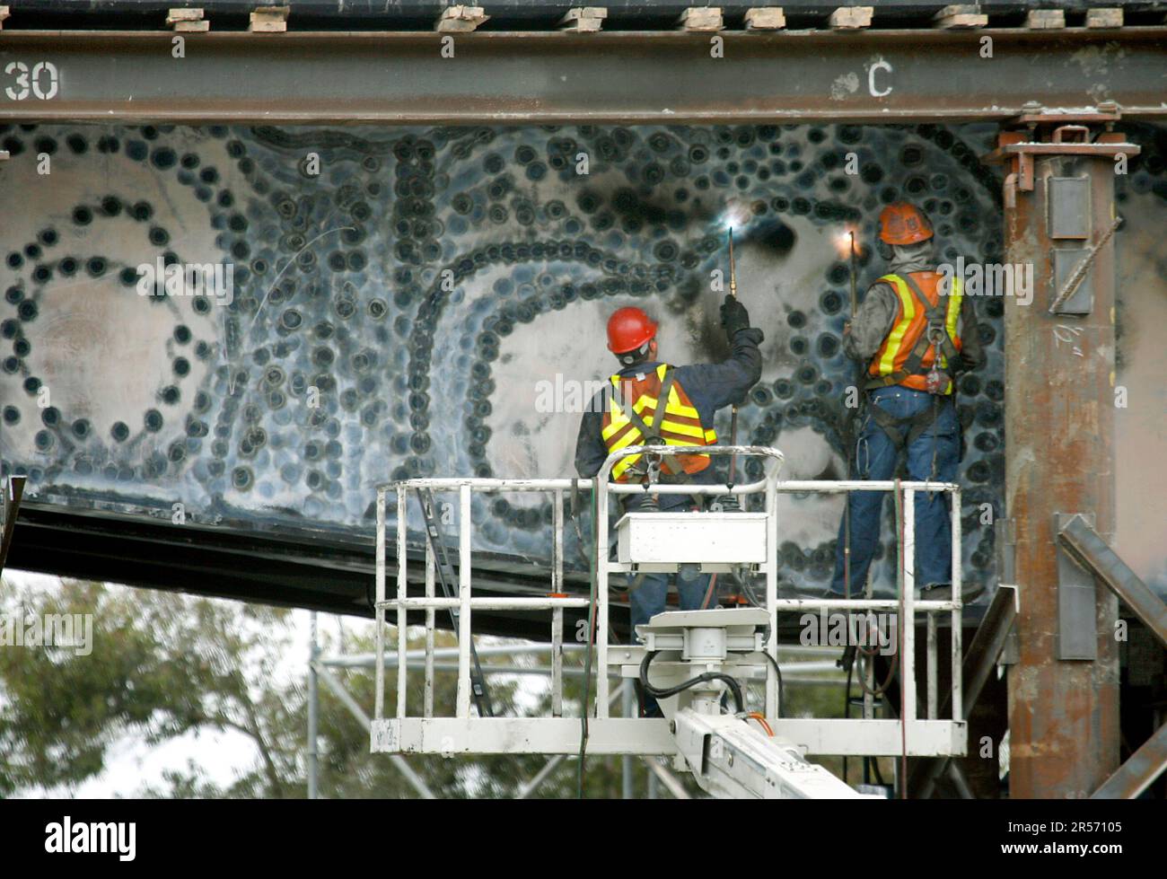 Welders create a mosaic pattern on a steel beam below the I-880 ramp as ...