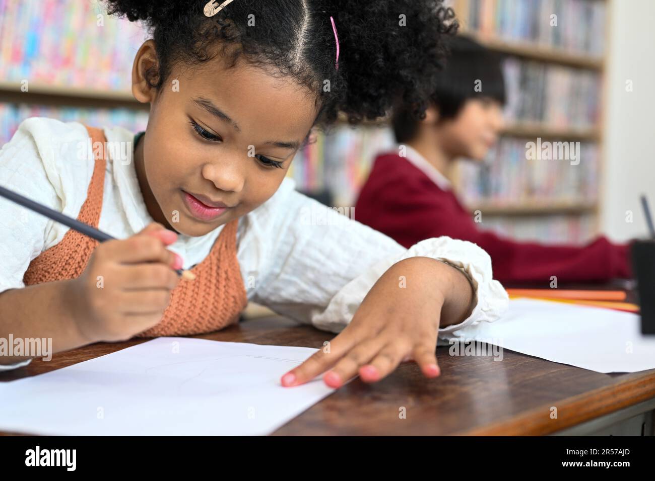 Cute pupils writing and painting on paper at desk in classroom Stock ...