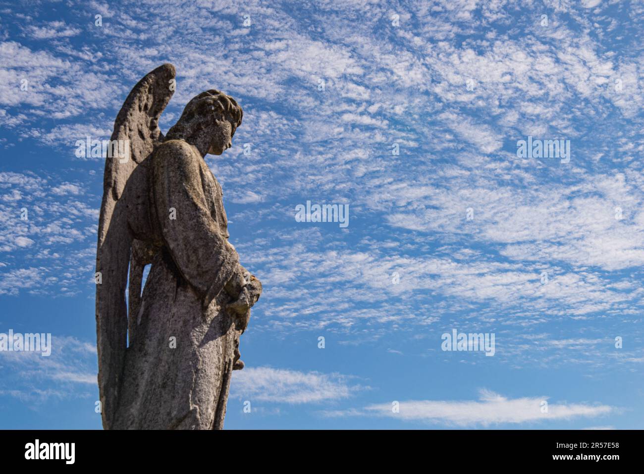 Stone angel in cemetery against a cloudy blue sky Stock Photo - Alamy