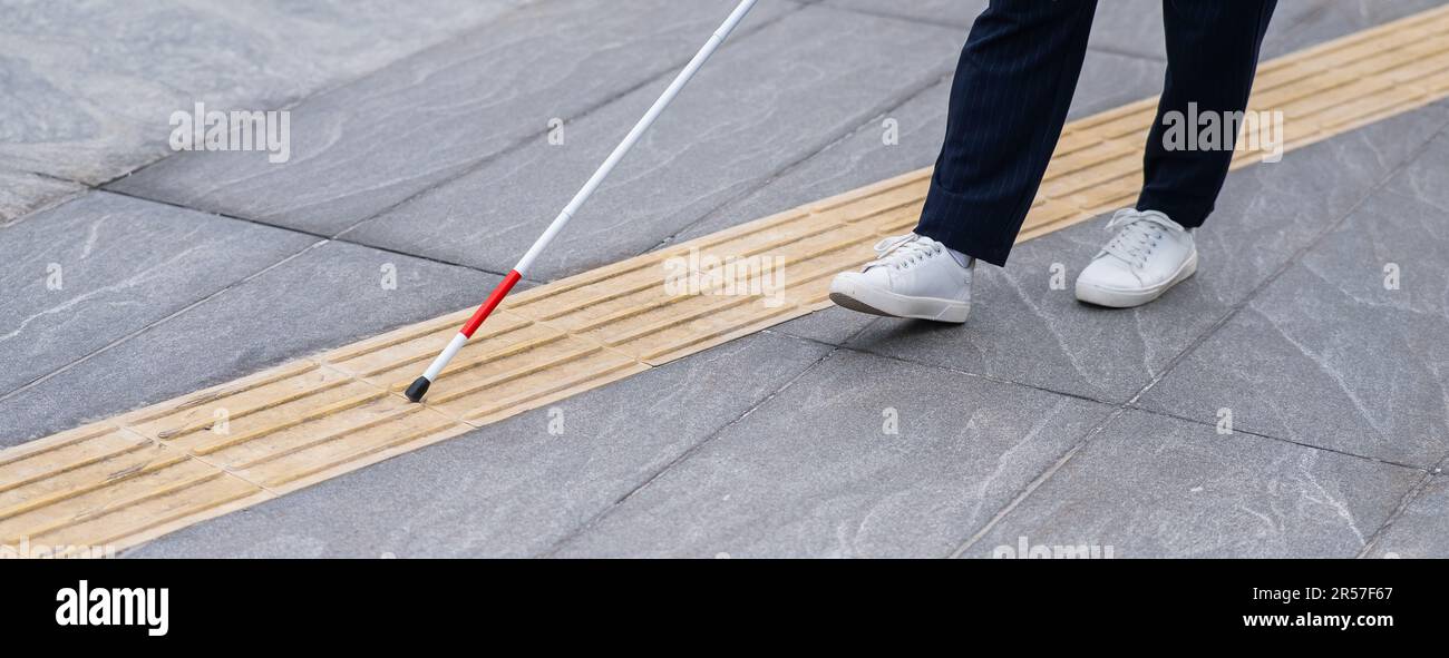 Close-up of the legs of a blind businesswoman walking along a tactile ...