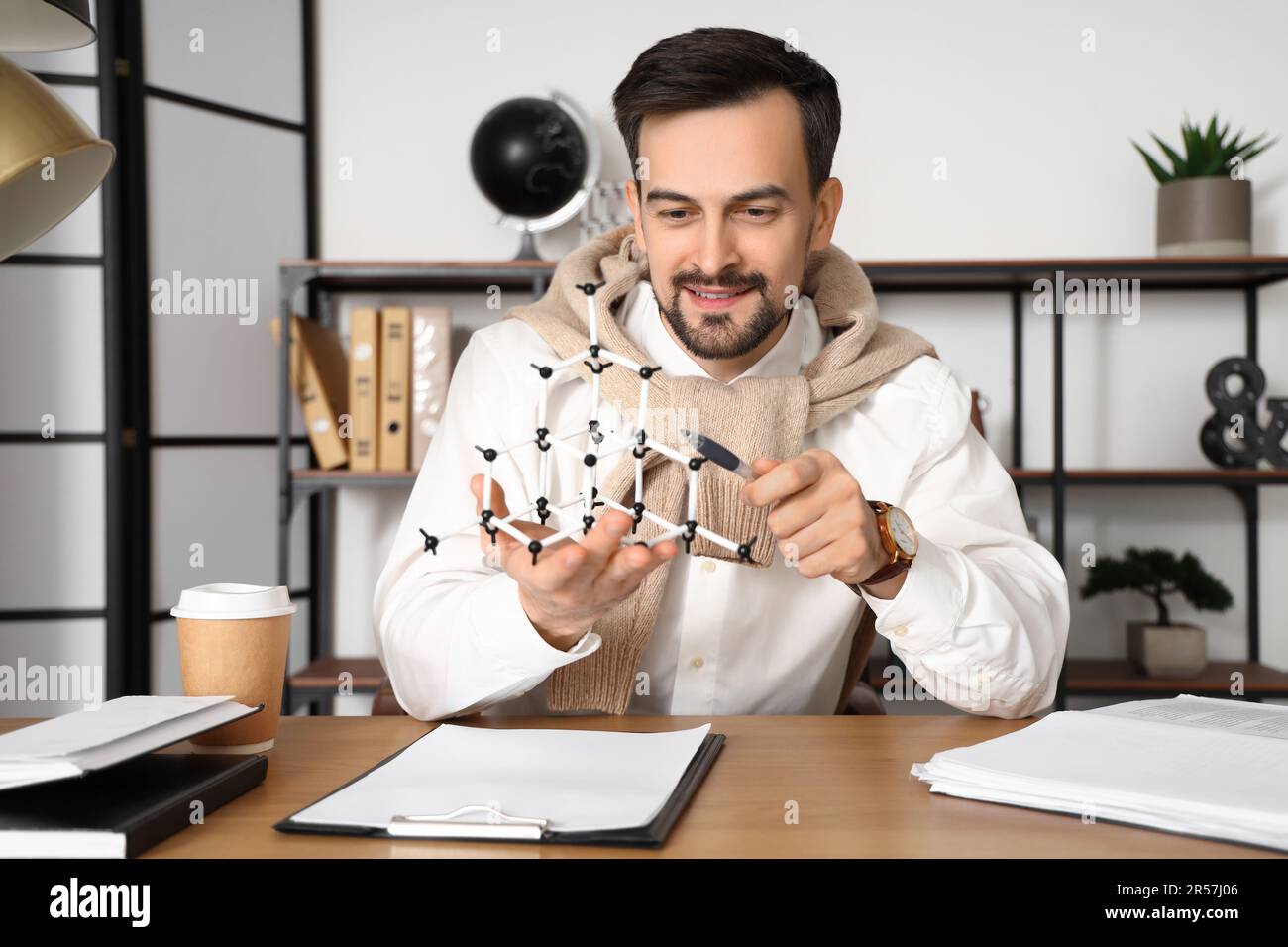 Male tutor with molecular model giving online Physics lesson at home ...