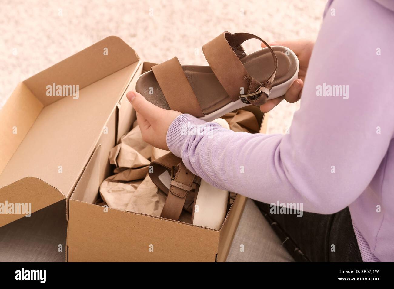 Woman taking brown suede sandals out of box in room Stock Photo - Alamy
