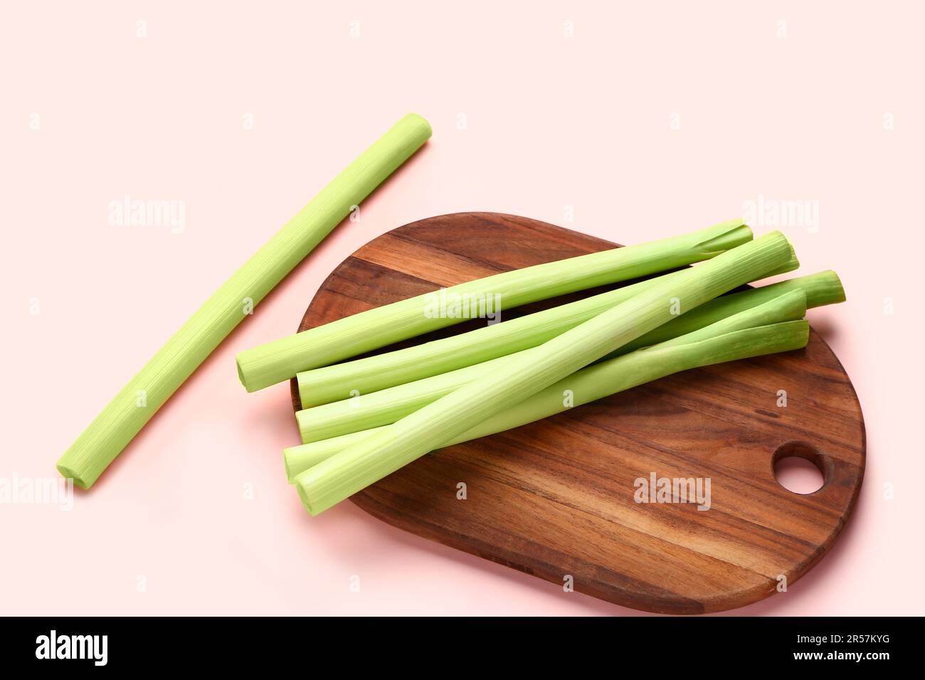 Board with fresh leeks on pink background Stock Photo - Alamy