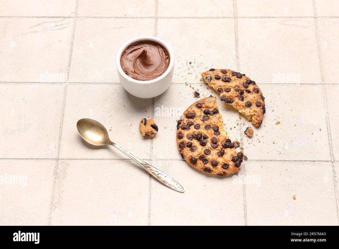 Broken cookie with chocolate cream and spoon on white tile background ...