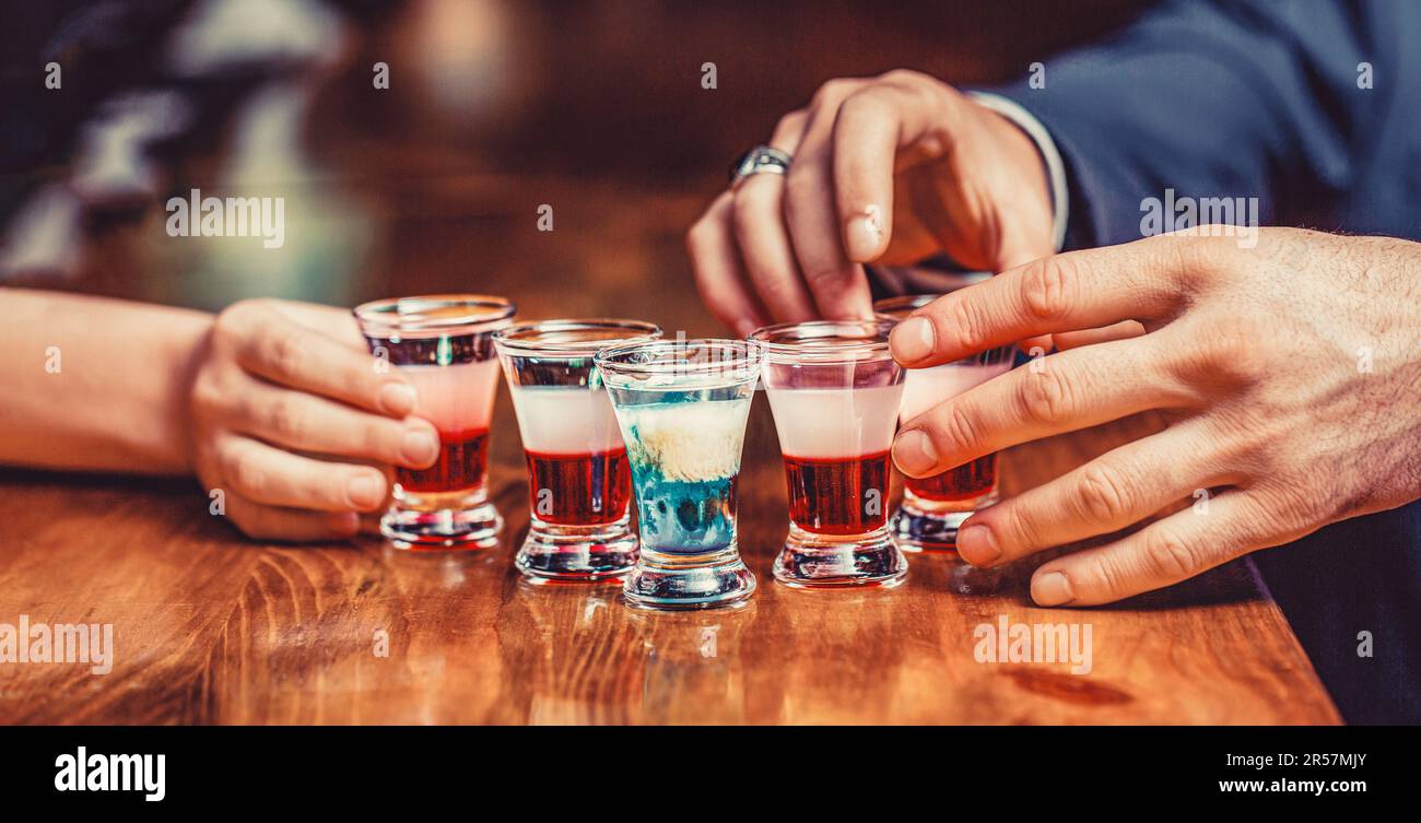 Male hands glasses of shot or liqueur. Friends drink shot or liqueur ...