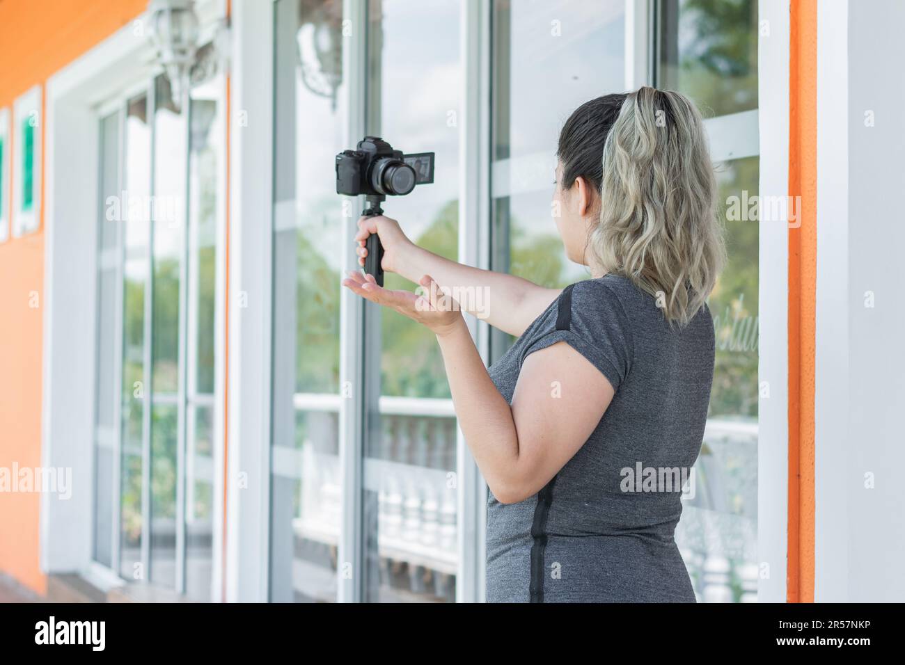 view of the back of a young latina woman taking a video of herself with ...