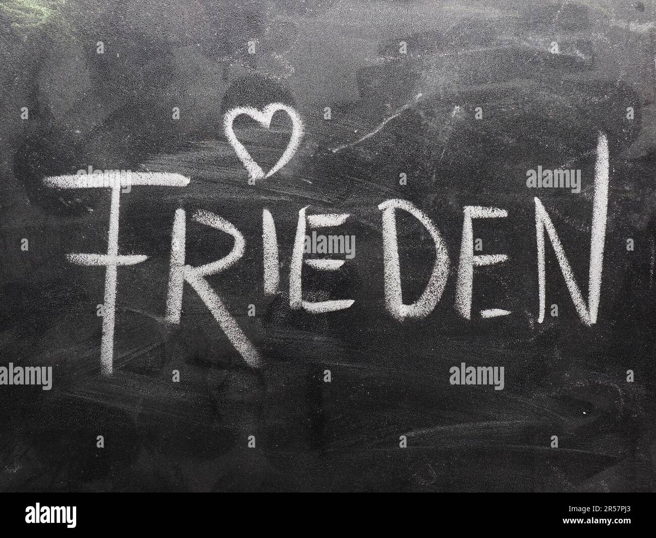 The German word peace with a heart shape on a chalkboard, world peace ...