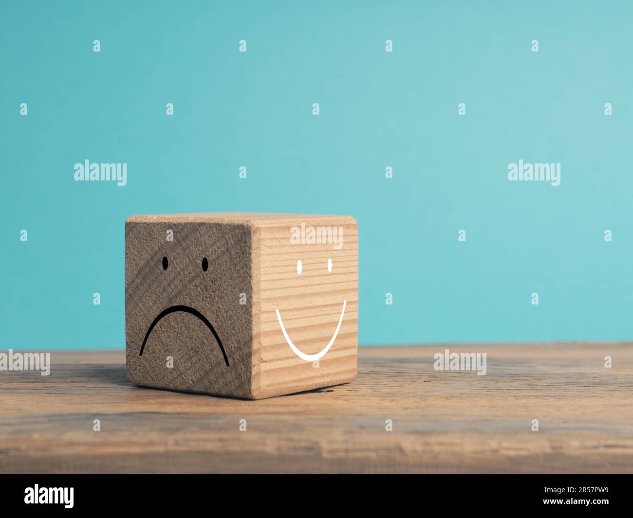 A wooden cube with light and dark side, once with smiling face and with ...