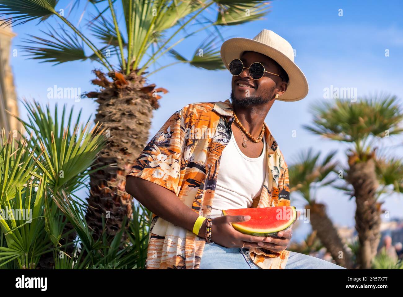 Black ethnic man enjoy summer vacation on the beach, wearing a hat and ...