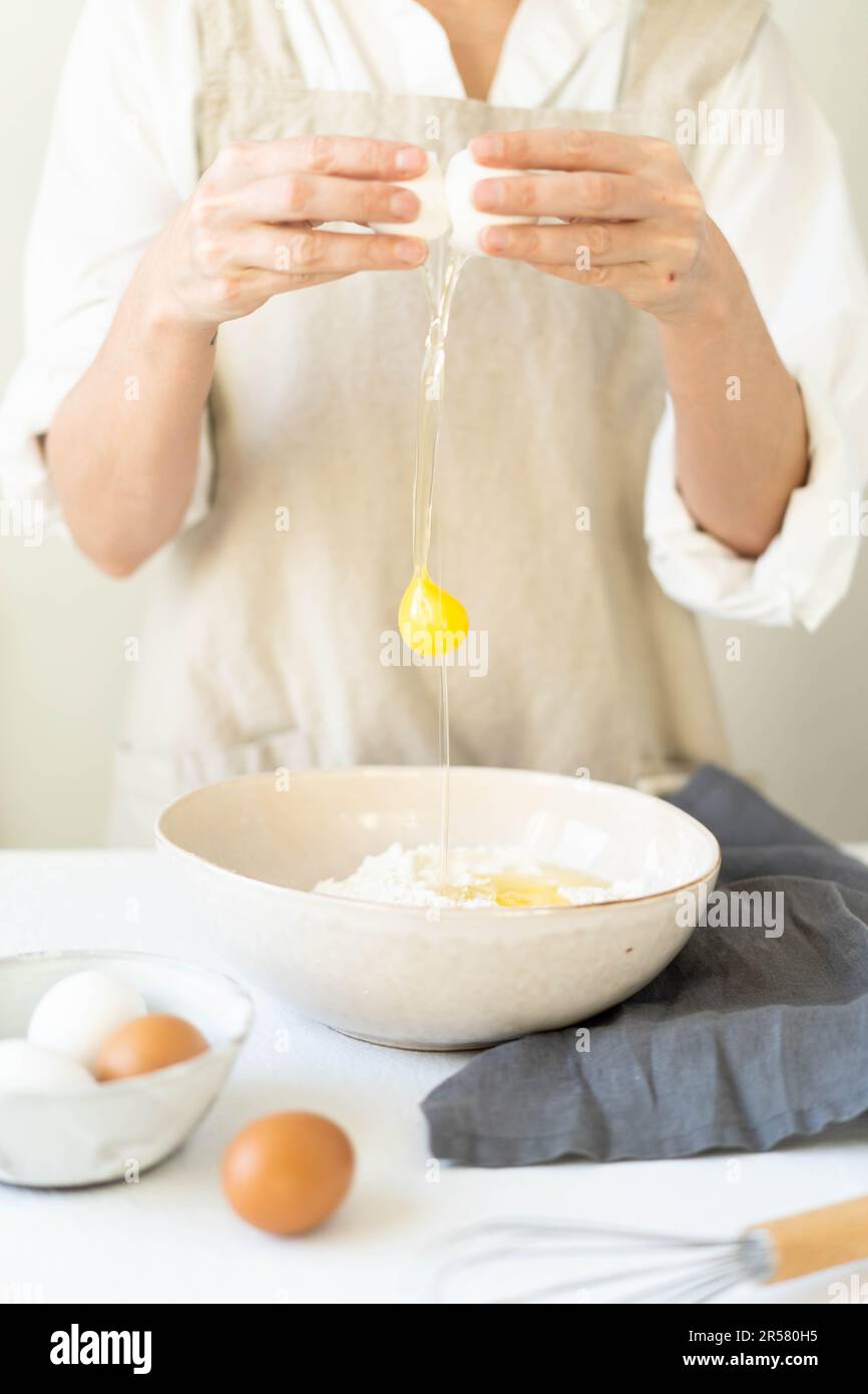 Cooking eggs with women's hands in a bowl of flour. Making a delicious ...