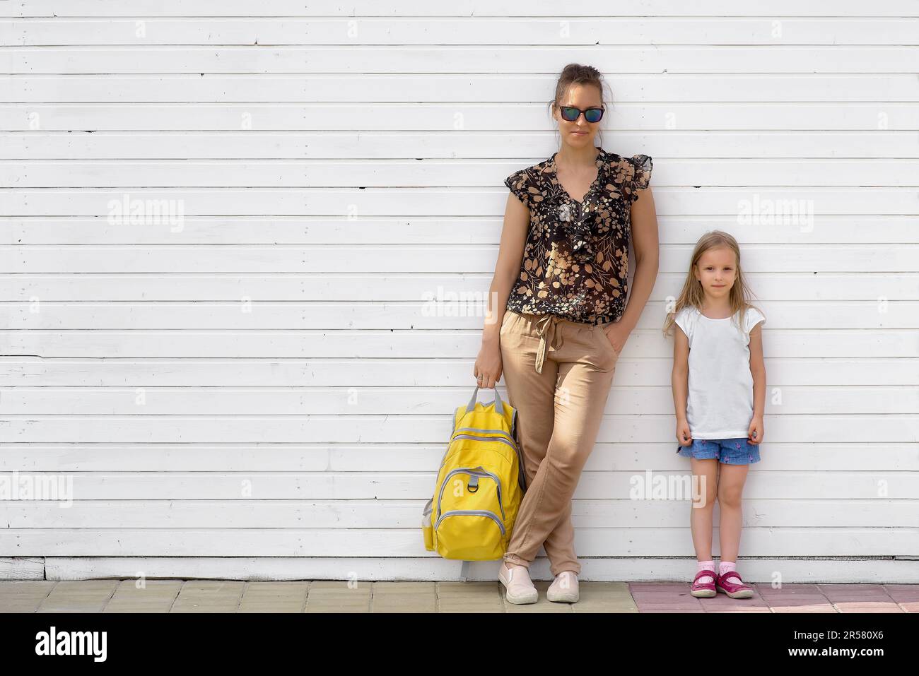Beautiful young mother and her cute little daughter leaning against a ...