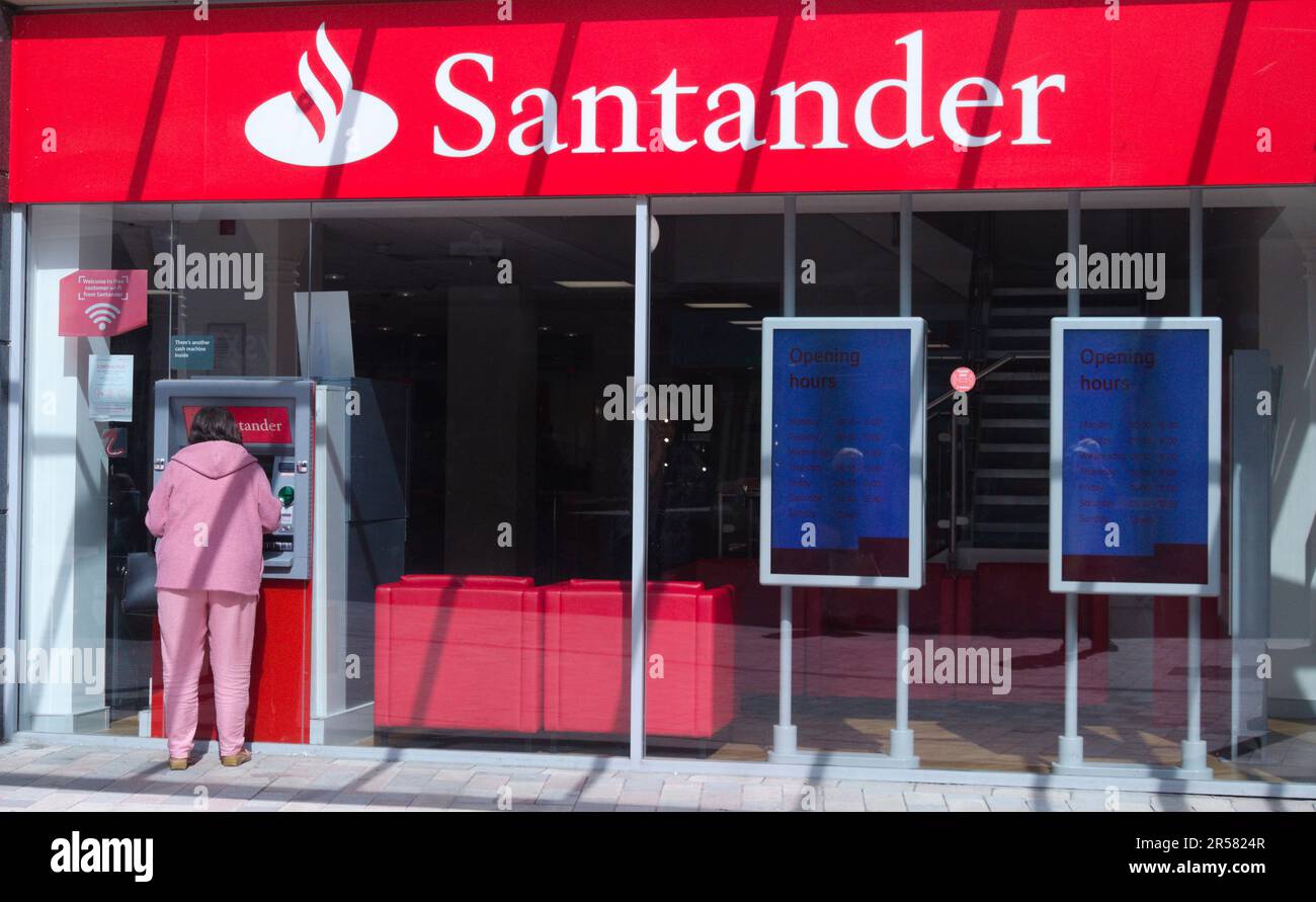 A woman uses an atm at Santander Bank in Stockport, Greater Manchester ...