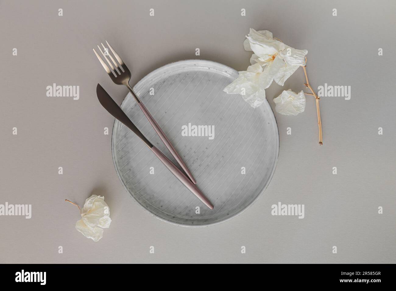 Golden modern cutlery, dried orchid branch and ceramic plate Stock ...