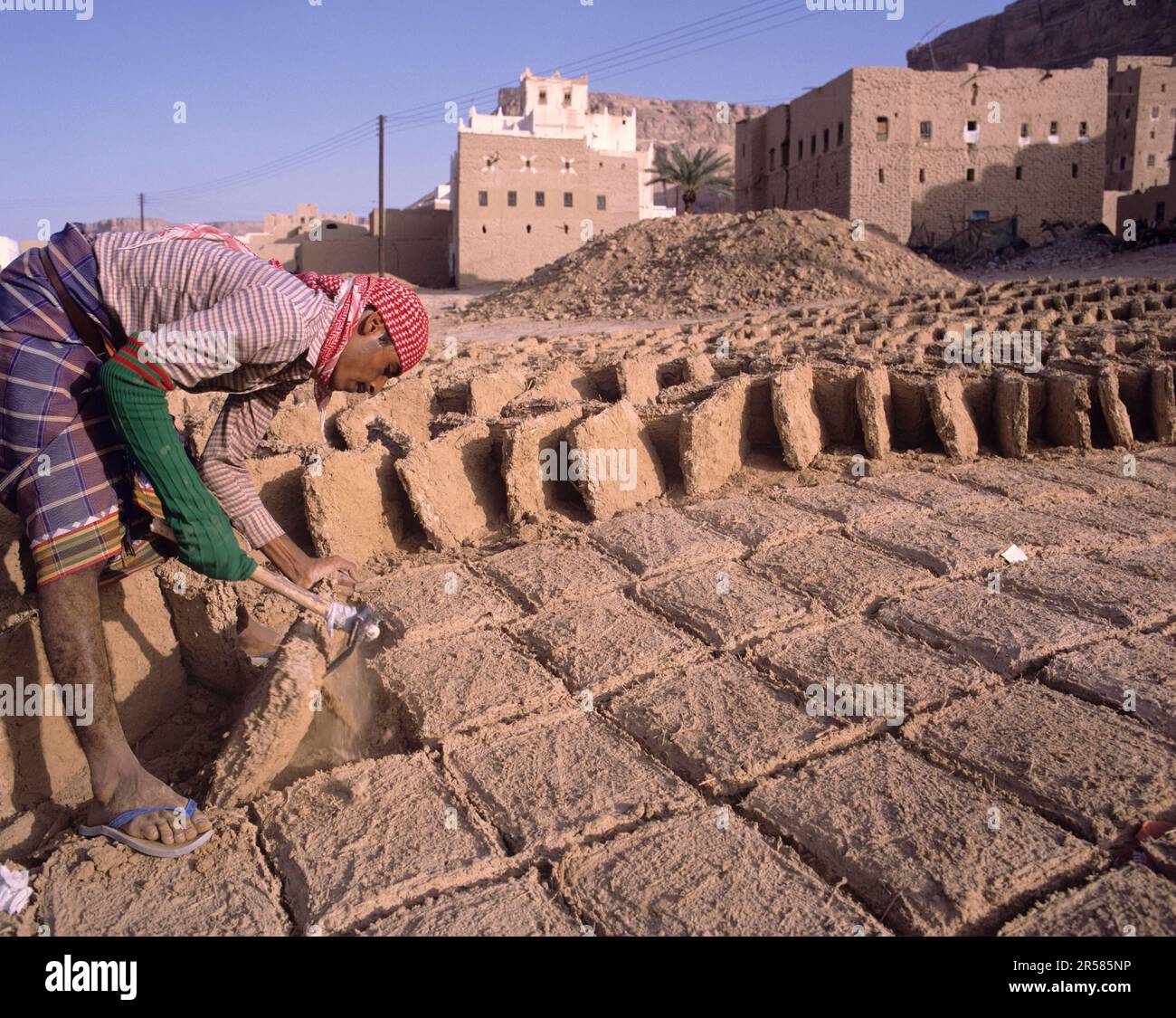 Man in traditional dress making air-dried mud bricks in Hadramaut, near ...