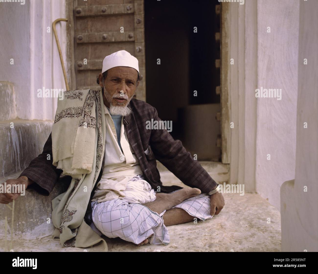 Man in traditional dress sitting in front of the house door, Yemen ...