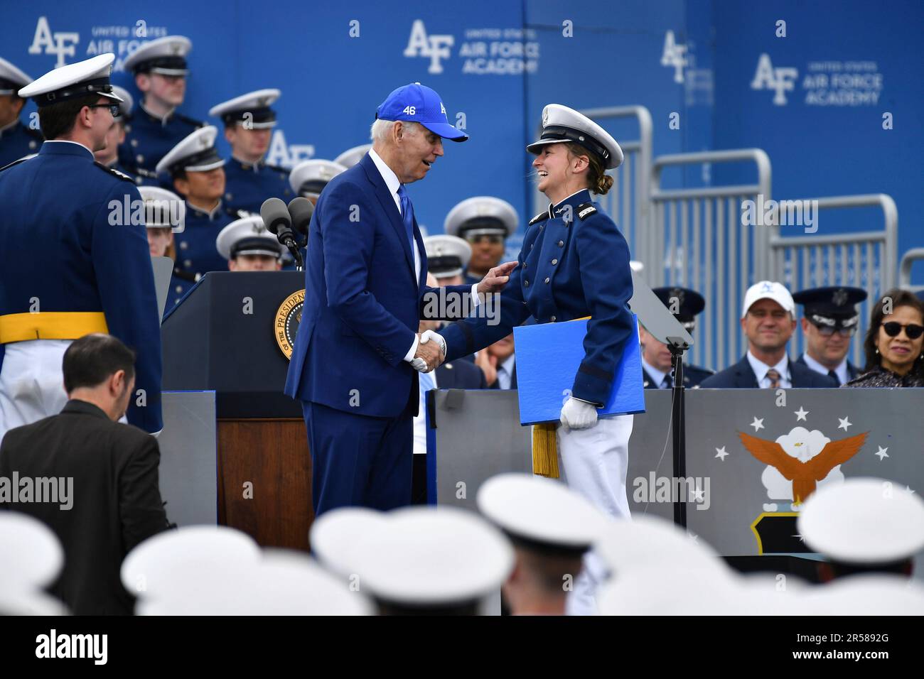 A cadet receives her diploma and shakes hands with President Joe Biden ...